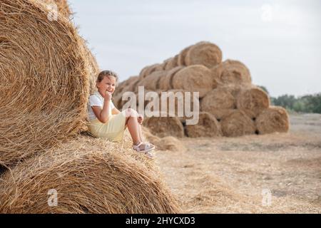 Girl sitting on the field and picking flowers Stock Photo - Alamy