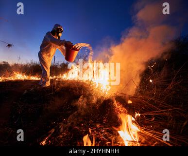 Research scientist fighting fire in field with blue night sky on ...