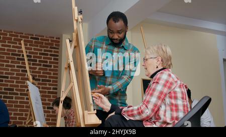 Art class teacher guiding senior student to draw sketch on canvas. Old ...