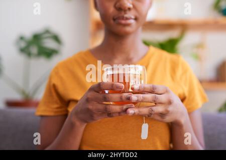 A young woman makes a cup of rooibos or red bush tea for health and ...