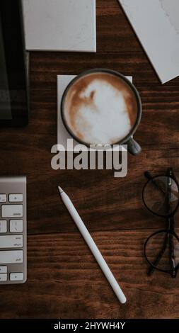 Top view of mug of Nescafe with computer and pen with camera on a table ...