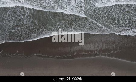 Aerial view of the wavy sea hitting the sandy beach on the coast Stock ...
