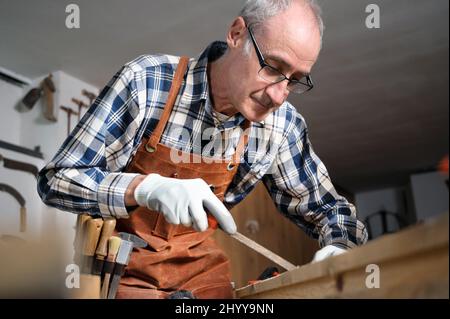 Carpenter filing a plank of wood in his Workshop. High quality ...