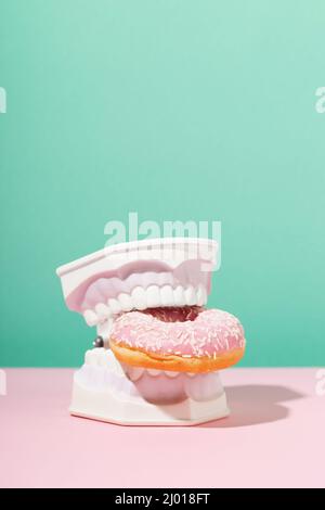 Plastic jaws hold sweet pink donut in teeth. Dental health, dentistry ...