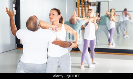 Young woman practicing elbow blow with wristlock to opponent in gym ...