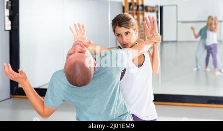 Young woman practicing palm strike with man in self defense training ...