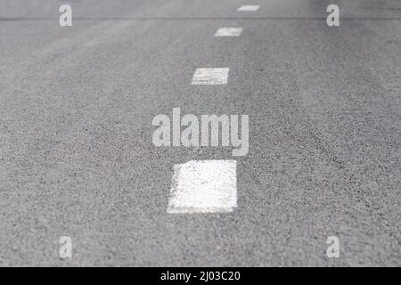 Road markings. An intermittent white stripe on an asphalt road. Urban ...