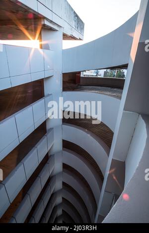 Bottom view of circular car parking garage against white clouds and ...