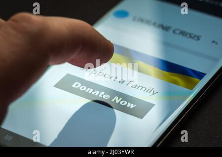 Close-up finger pressing donate icon button on smartphone screen ...