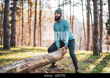 Strong sporty man is lifting tree stump Stock Photo - Alamy