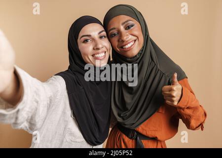 Multiracial muslim women gesturing while taking selfie photo on ...