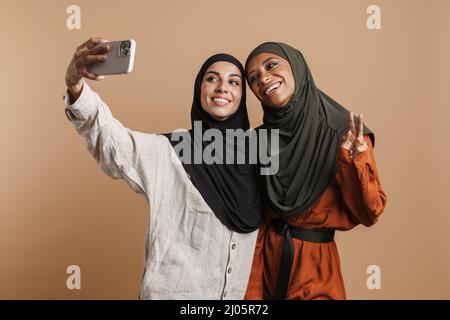 Multiracial muslim women gesturing while taking selfie photo on ...