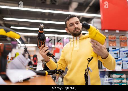 A man chooses a power tool in a hardware store Stock Photo - Alamy