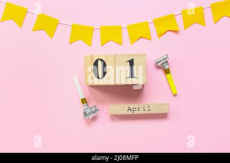 Composition with party whistles and calendar with date 1 APRIL on pink ...
