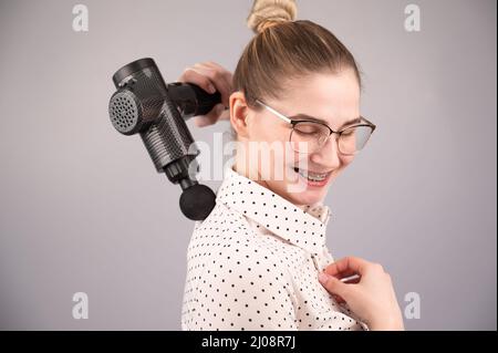 Caucasian woman uses a massager gun for pain in the muscles of the arm ...
