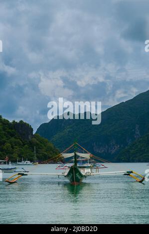 Traditional Filipino boat on Calm sea water in front of island and ...