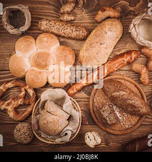 Many mixed baked breads and rolls on rustic wooden table. Top view ...