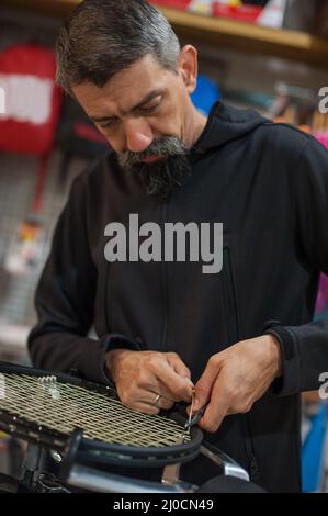 Stringing tennis racket. Tennis stringer tying knots and cutting string ...