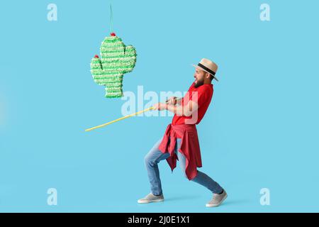 Handsome man breaking Mexican pinata on color background Stock Photo ...