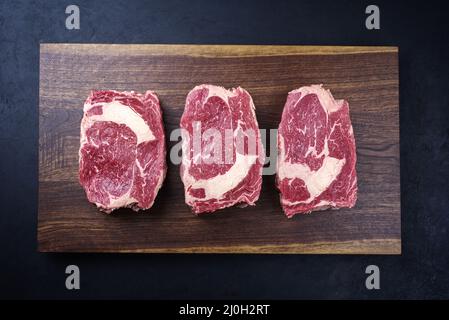 Modern style raw dry aged wagyu rib-eye beef steaks offered as close-up ...