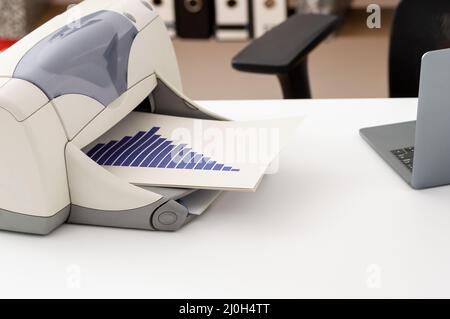 Shot of diagram sheets of paper coming out of a computer printer at ...