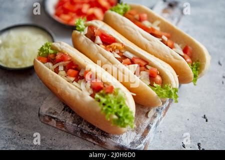 Assortment of three tasety hot dogs, placed on wooden cutting board ...