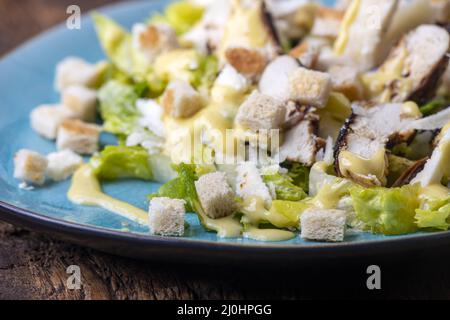 Plate with tasty Caesar salad on color wooden background Stock Photo ...