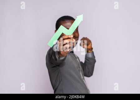 Excited African man holding an upward graph symbol and showing victory ...
