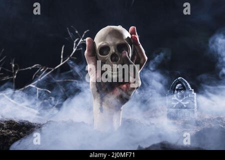 Hand sticking out ground holding skull Stock Photo - Alamy