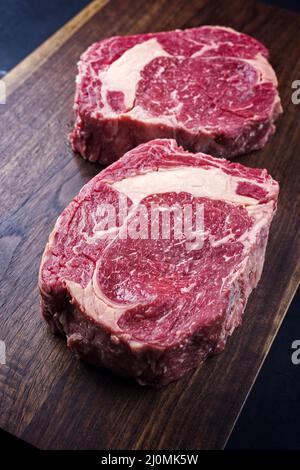 Modern style raw dry aged wagyu rib-eye beef steaks offered as top view ...