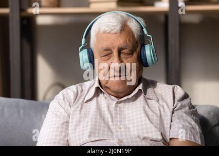 Middle-aged man listens to music in wireless headphones, rhythmically ...