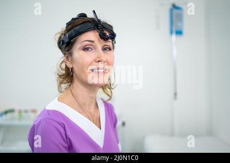 Medical worker of ENT clinic middle aged Caucasian female in purple ...