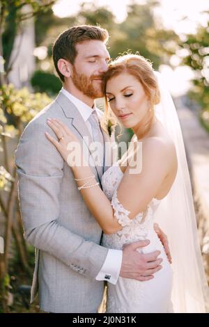 Groom hugs bride while standing on the stones against the background of ...