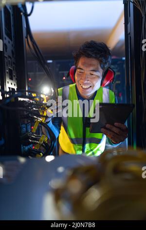 Asian male engineer using smartphone flash while inspecting the server ...