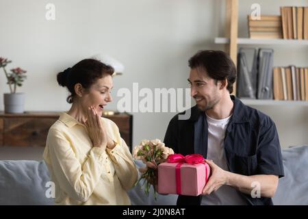 Excited young woman mother getting wrapped gift box present from ...
