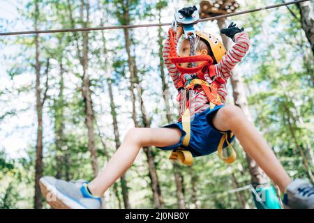 Boy hanging on the zip line holding on to the safety rope with his ...
