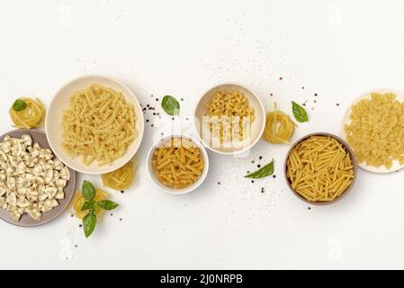 Bowls with different types of uncooked pasta on wooden background Stock ...