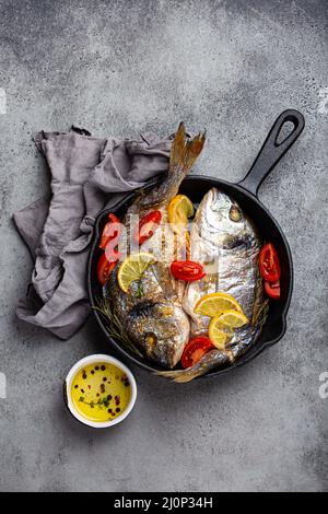 Roasted sea bream fish with herbs on a cutting board. Black background ...