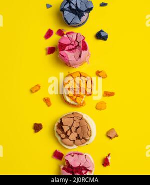 Broken round macarons with crumbs on a yellow background, delicious ...