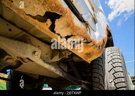 Rusty part of the car body with through-out corrosion. Background for ...