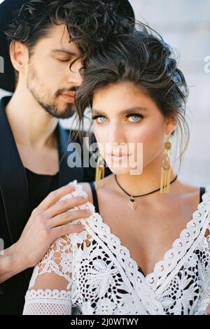 Groom in a hat hugs the bride in a white wicker dress Stock Photo - Alamy