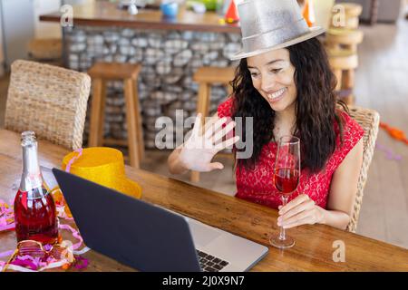 Smiling biracial young woman waving hand during video call on laptop at ...
