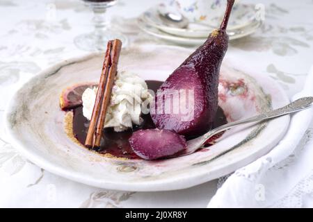 Traditional poarched pear in red wine sauce offered as close-up on a ...