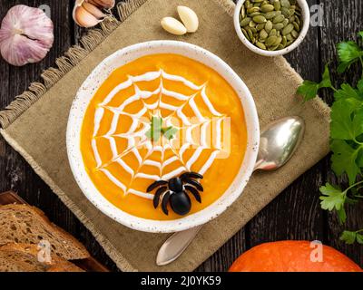 Funny food for Halloween. Pumpkin puree soup, spider web, dark old ...