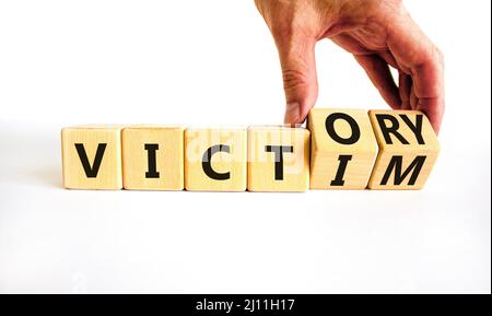 From victim to victory symbol. Businessman turns wooden cubes and ...