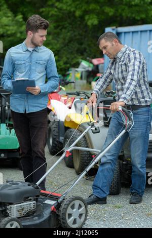 consultant shows a customer lawn mower in a store Stock Photo - Alamy