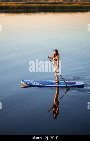 Portrait of woman paddle boarding on lake Stock Photo - Alamy