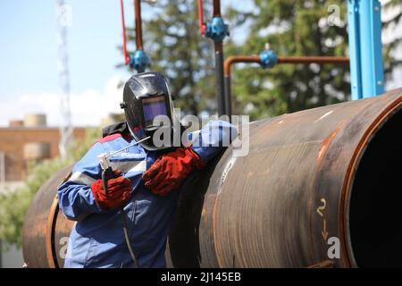 Male welder works. Welding joint of large diameter pipe. High pressure ...