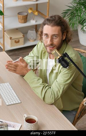 Male blogger using computer and microphone at home Stock Photo - Alamy