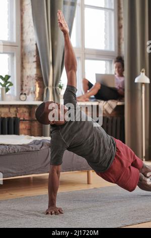 Doing side plank. Smiling African-American woman doing side plank while ...
